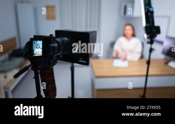 Camera on tripod filming a woman sitting at desk. Influencer creates a ...