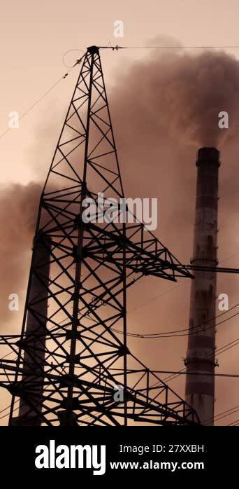 Transmission lines next to factory pipes with dark fumes.high pipes ...