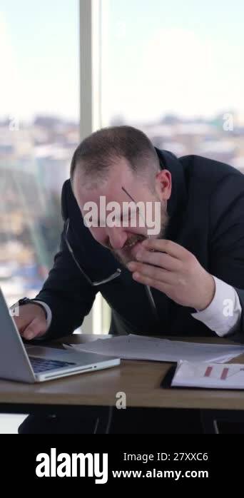 Man doing funny faces sitting in front of laptop. Mad businessman ...