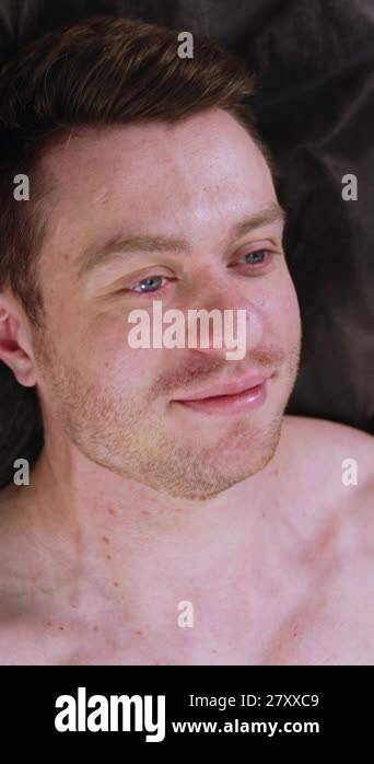 Mid-aged Caucasian man lies on the bed. Specialist in latex gloves puts ...