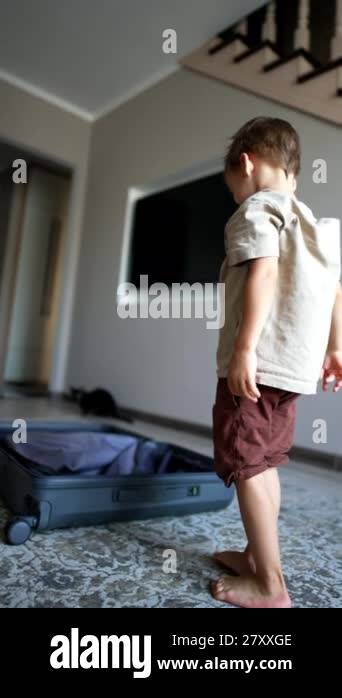 Cheerful baby boy opens a big suitcase. Lovely toddler kid gets into ...