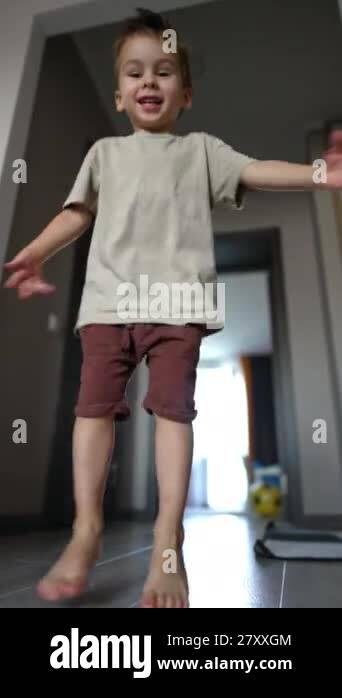Cheerful energetic kid jumps indoors. Low angle view. Smiling baby boy ...