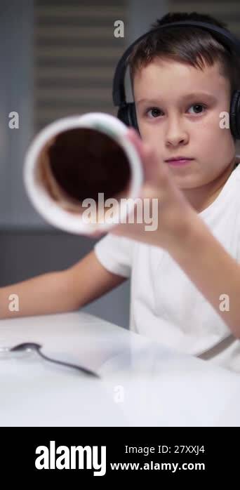 Kid eating and watching tablet. Boy eating dessert and looking at the ...