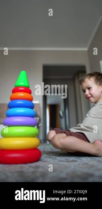 Baby boy sits on the floor building a colorful pyramid. Toddler kid ...