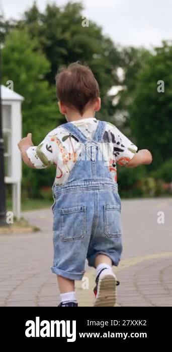 Baby toddler running around the beautiful flower bed in the park ...
