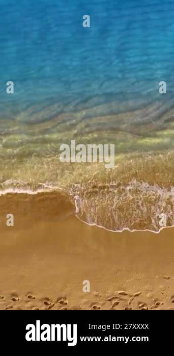 Waves of the sea splash on the sandy beach. Afro-American man stands in ...
