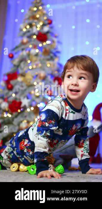 Happy baby playing on the floor near the Christmas tree. Lots of ...
