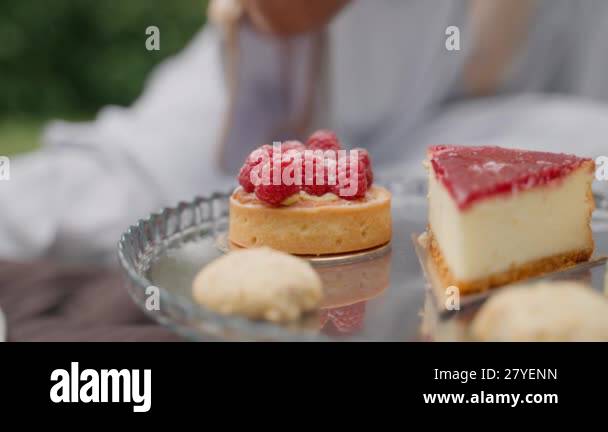 A womans hand gently picks a fresh raspberry from beautifully arranged dessert plate during ...