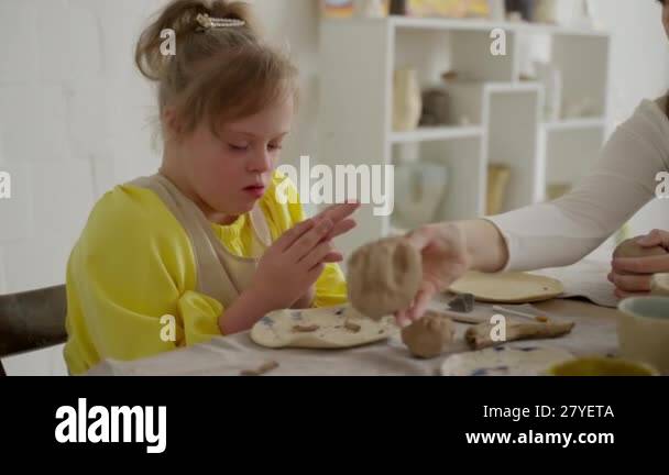 Young girl with Down syndrome, wearing yellow dress and apron, taking a ...