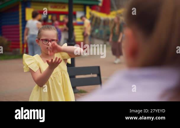 Girl with Down syndrome in yellow dress uses gestures to show mom that ...