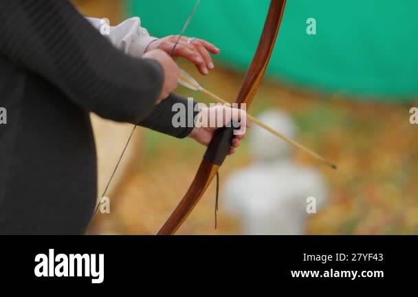 A man is holding a bow and arrow, preparing to shoot. The scene is set ...
