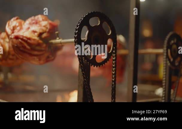 A chain is attached to a spit, which is cooking meat. The chain is ...