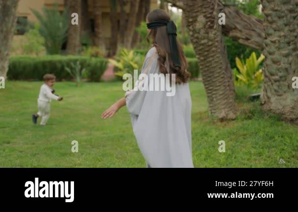 Boy laughs joyfully as he runs across lush garden with a toy in hand ...