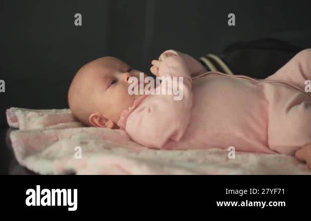 Baby in a pink onesie rests on a soft blanket, preparing for swim ...