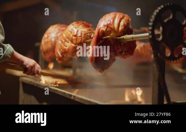 A person is cooking meat on a spit. The meat is being cooked over an ...