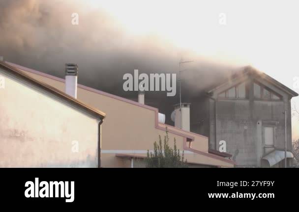 Rovigo, Italy 1 January 2025: Black smoke billowing from the roof of a ...