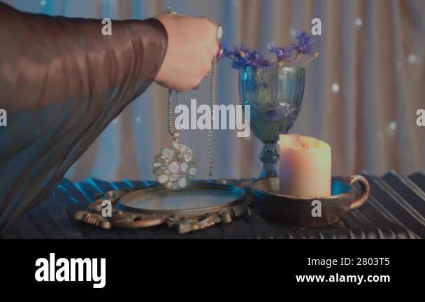 The sorcerers hand moves the medallion over the mirror to perform a ...