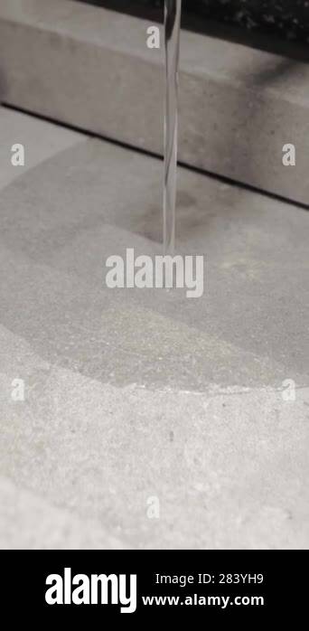 Vertical video. A closeup image of water cascading onto a textured ...