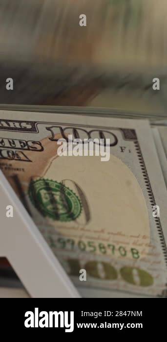 A close-up of a hundred-dollar bill lying on a surface inside a cash ...