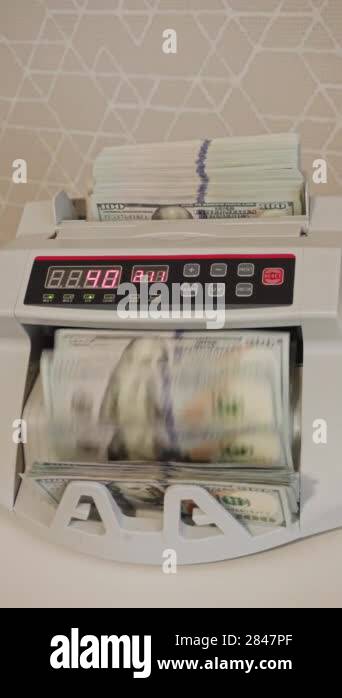 A cash counting machine processes newly stacked bills, displaying the ...