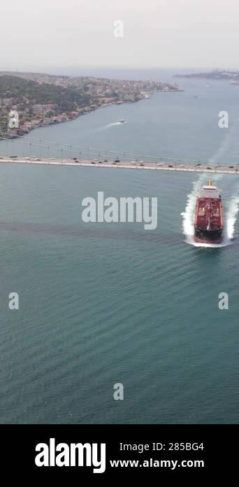 Aerial shot of a large transport ship crossing the Bosphorus, a city by ...