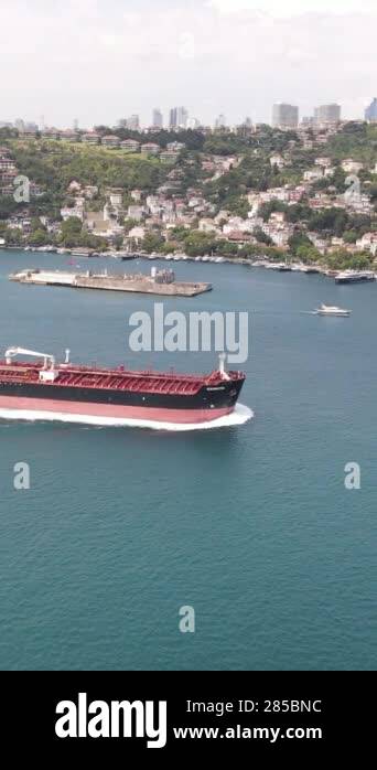 Aerial shot of a large transport ship crossing the Bosphorus, a city by ...