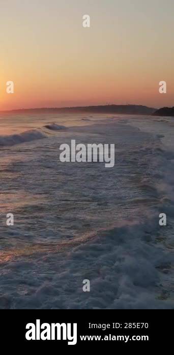 Aerial drone shot of the choppy sea at sunset, colorful sunset scenery ...