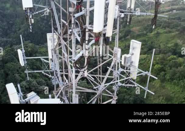 A tall communication tower equipped with multiple antennas, standing prominently on a mountain ...