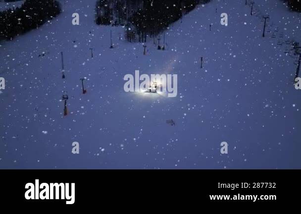 Aerial view of working snowcat on snowy alpine ski slope at winter ...