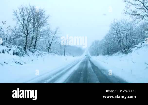footage of a snowstorm as seen from inside a car driving on a snowy ...