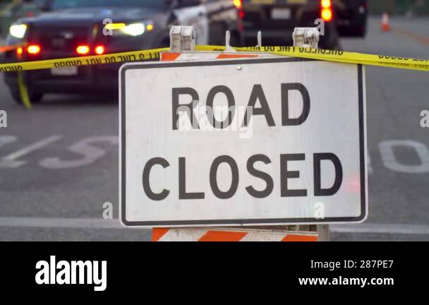 A detailed scene of a road closure enforced by law enforcement vehicles ...