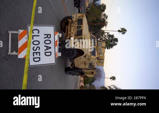 A prominent "Road Closed" sign, flanked by caution tape and a military ...
