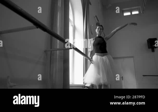 Prima ballerina in white skirt stretching practicing ballet positions ...