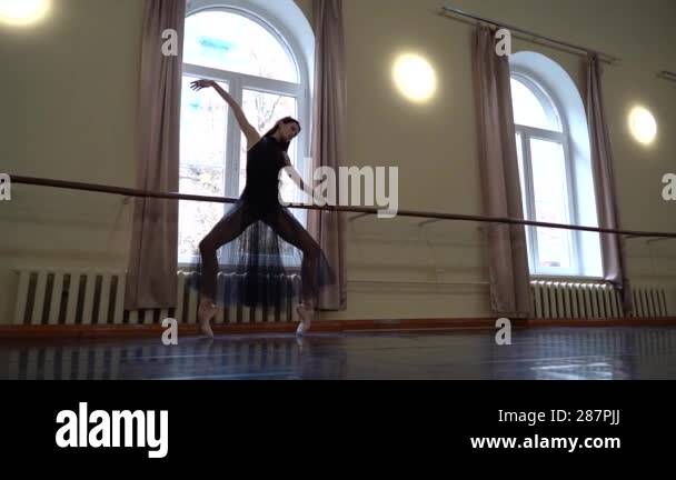 Prima ballerina in white skirt and pointe stretching practicing ballet ...