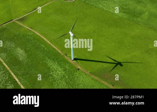 Cinematic aerial view of white rotating windmill blades generating renewable energy on scenic ...