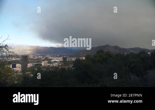 A dramatic aerial shot presents an expansive urban landscape with smoke ...