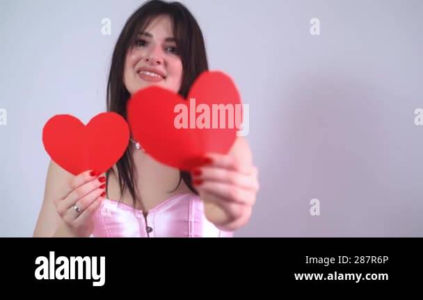 Girl in pink holding a red heart in each hand, symbolizing Valentines ...