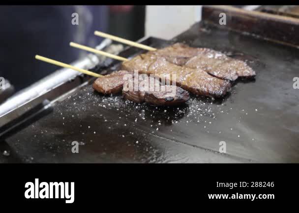Slow motion of chef grilling skewered beef or meat with a blowtorch ...