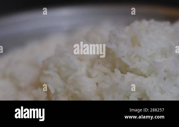 A close up of freshly cooked steaming white rice being scooped with a ...