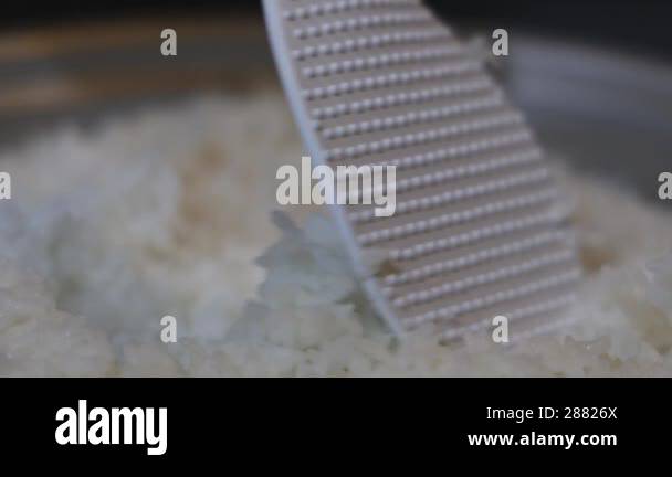A close up of freshly cooked steaming white rice being scooped with a ...