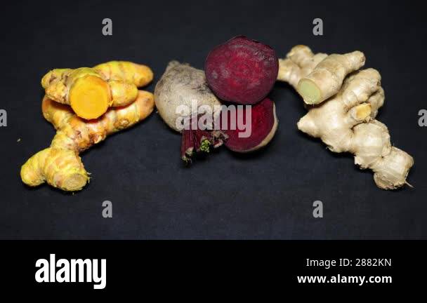fresh raw turmeric, beetroot, and ginger in studio light shot on black ...