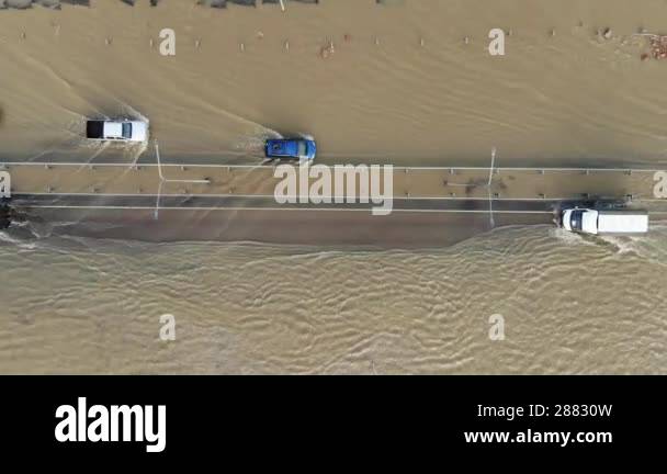 cars and trucks driving along a flooded highway during floods and ...