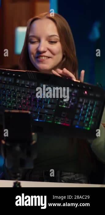 Vertical video Gen Z girl presenting RGB lit mouse and keyboard while ...