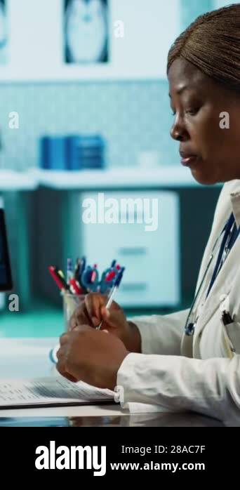 Vertical video Female general practitioner examining medical data with ...