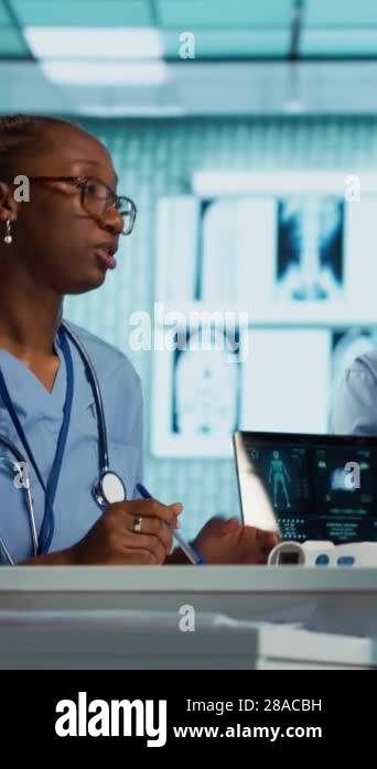 Vertical video Group of healthcare specialists in scrubs analyzing ...