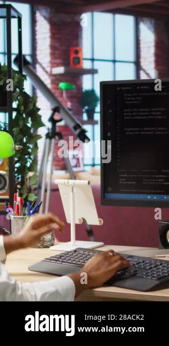 Vertical video Software developer wearing headphones using computer at home for artificial ...