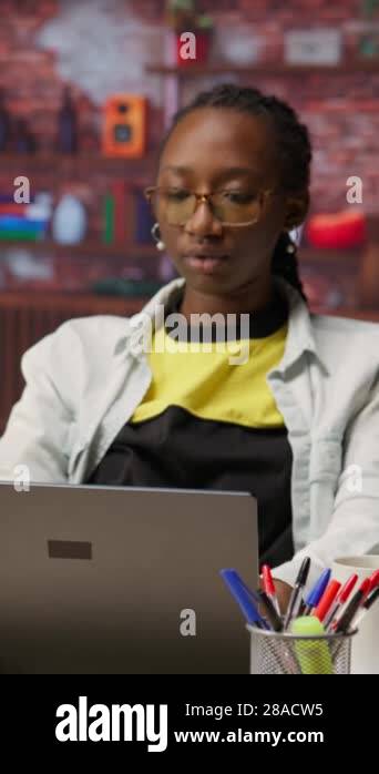 Vertical video Happy woman drinking coffee, enjoying watching TV show ...