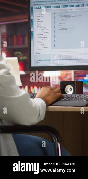 Vertical video Programmer wearing headphones types code into PC ...