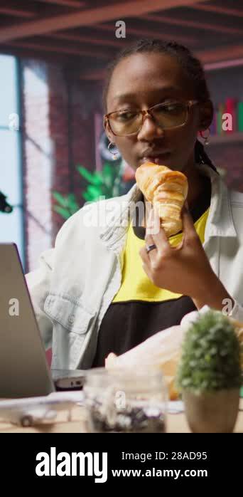 Vertical video Busy freelancer in home office eating snack on the go ...