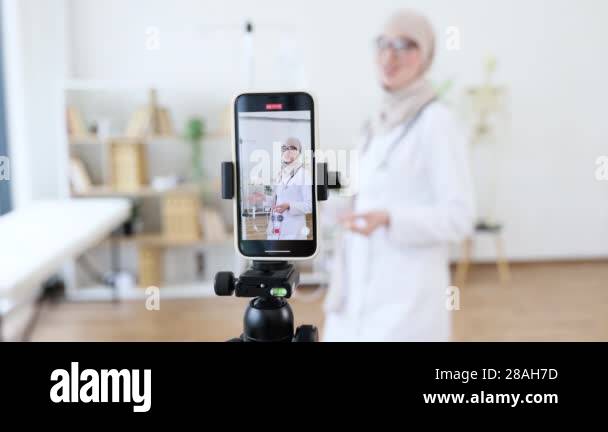 Muslim woman in white coat creating instructional video on medical ...